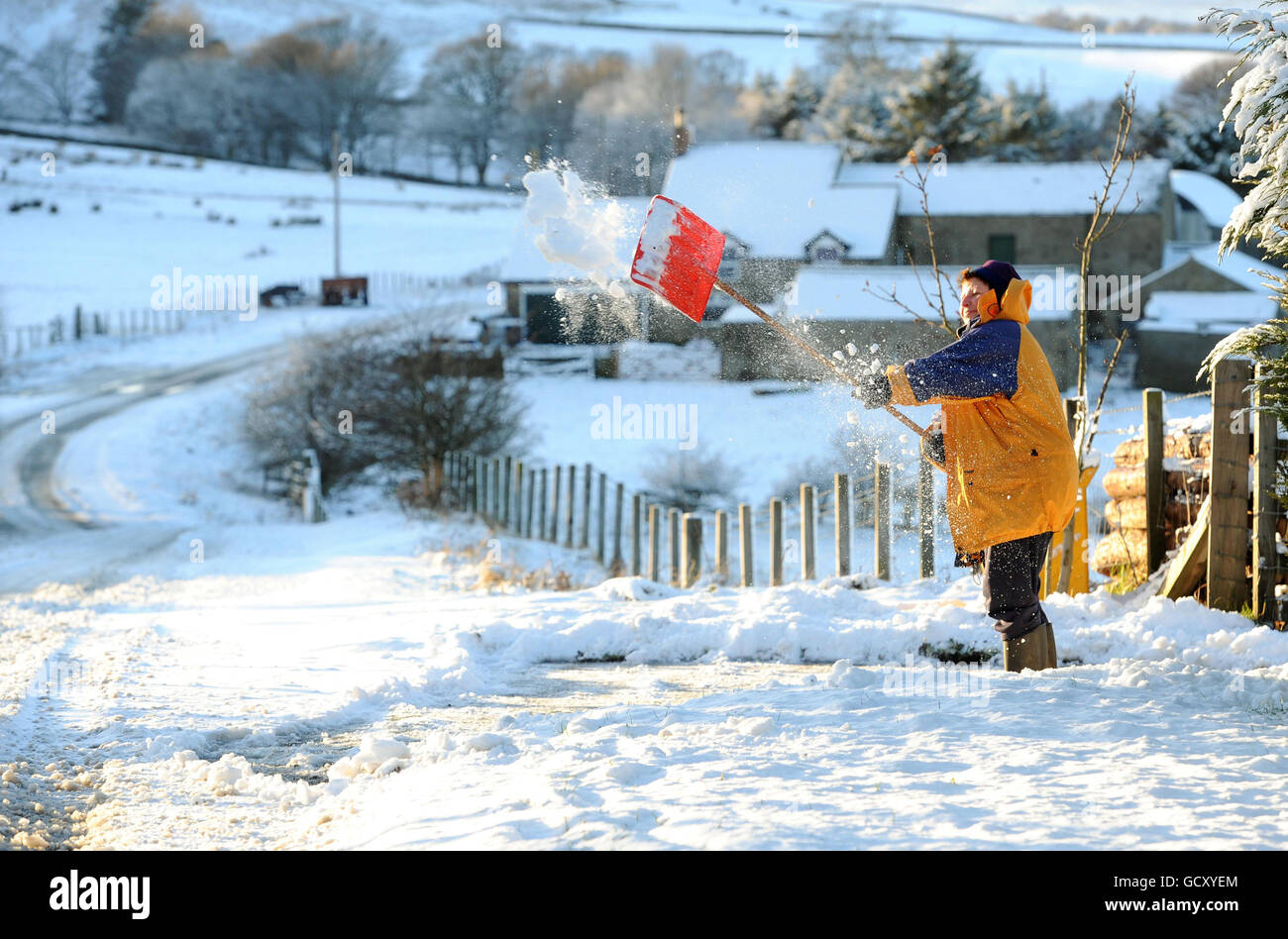 A woman clears the snow from her driveway in Rowley in County Durham as ...