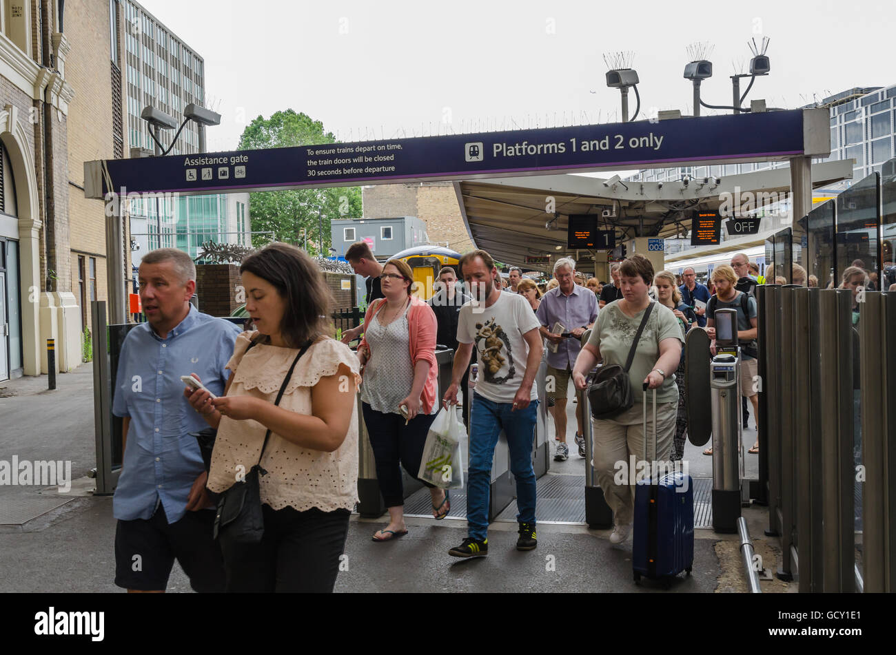 People pass through the ticket barriers at Victoria Station in London ...