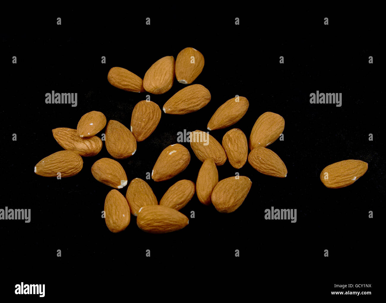 Unskinned unblanched whole natural almonds scattered on a black ...