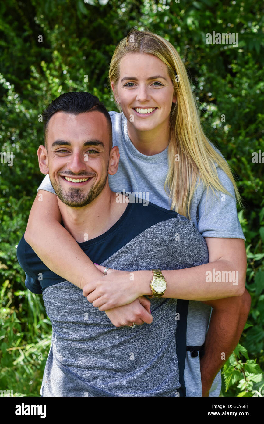Smiling blonde woman cuddling boyfriend from behind Stock Photo - Alamy