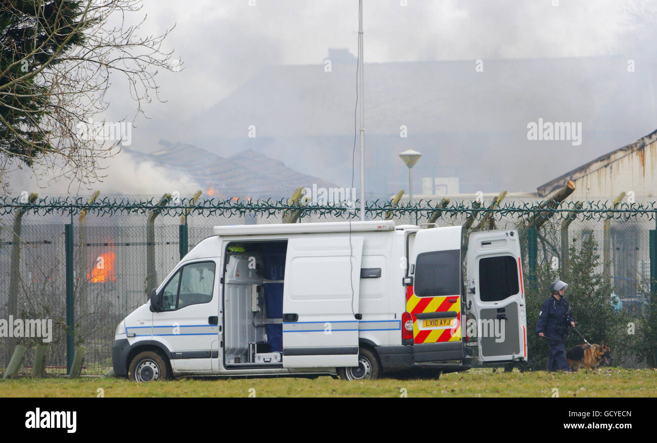 A specialist prison office dog handler walks past a burning gymnasium ...