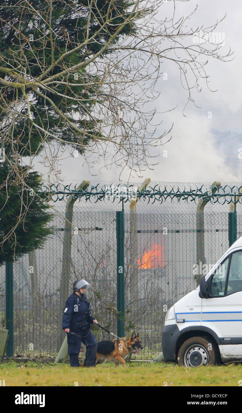 A specialist prison office dog handler walks past a burning gymnasium ...
