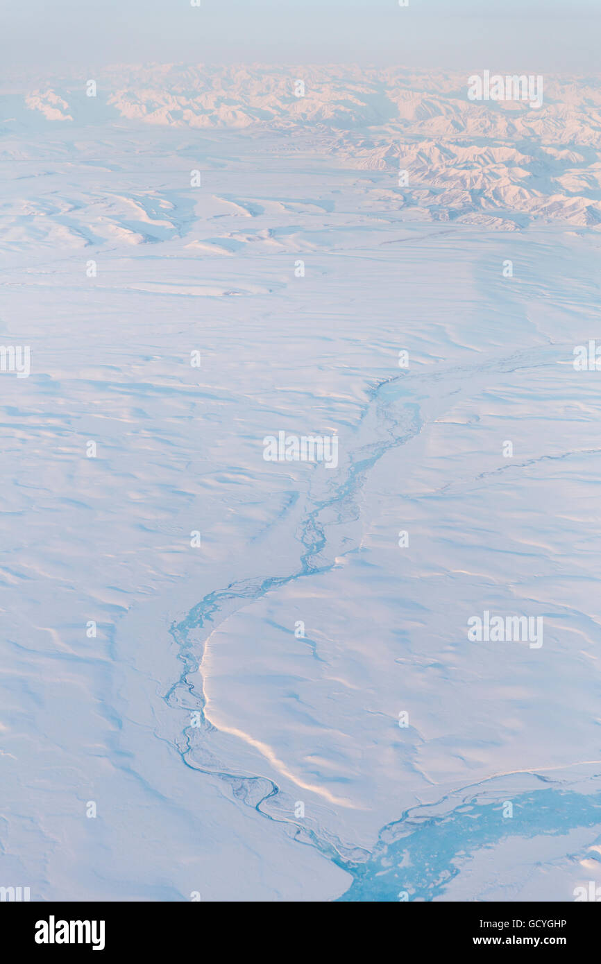 Aerial view of a partially frozen river flowing through a snow covered ...