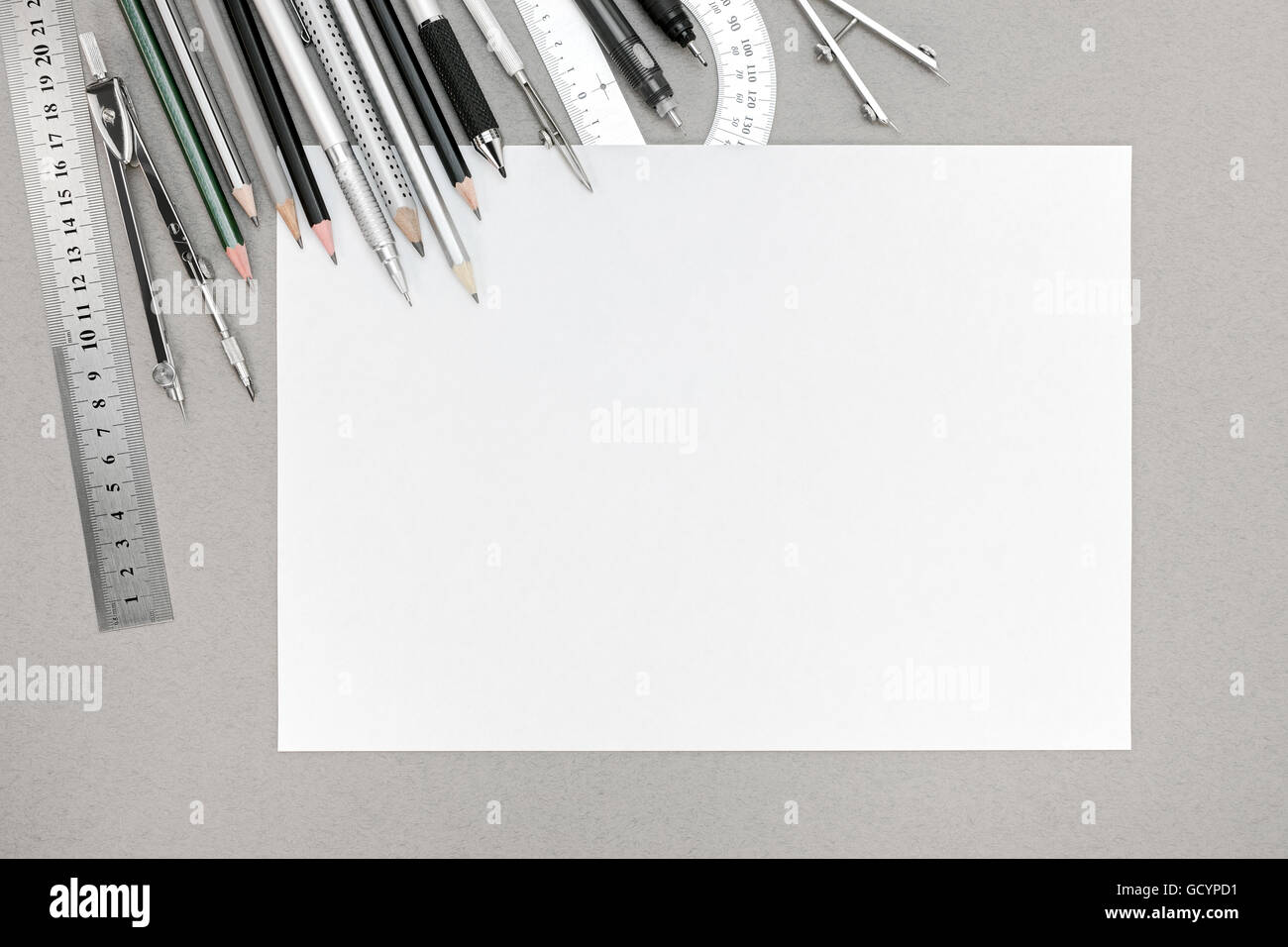 top view of gray desktop with with blank white paper and various ...