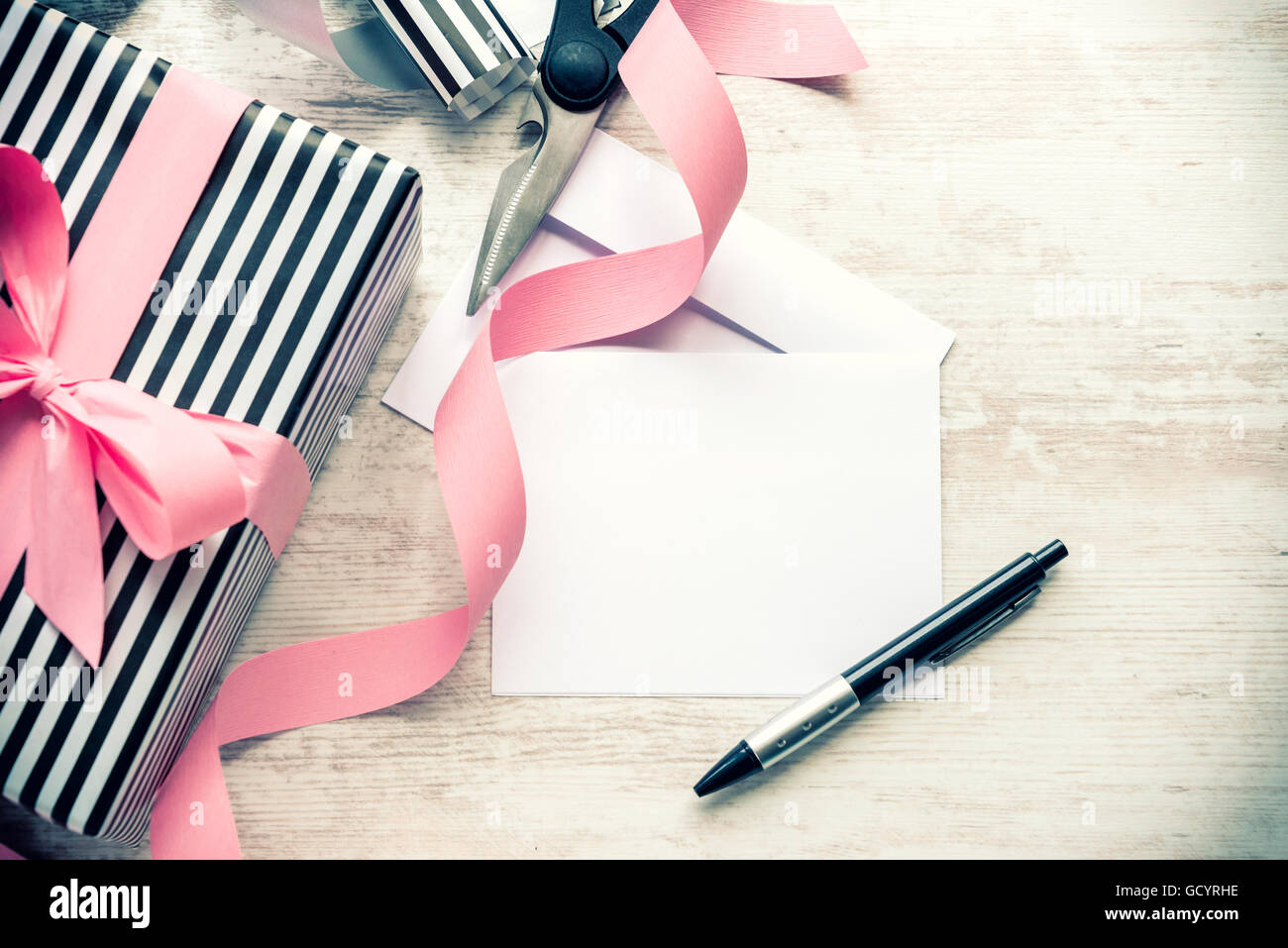 Empty greeting card. Wrapped gift and wrapping materials on a white ...