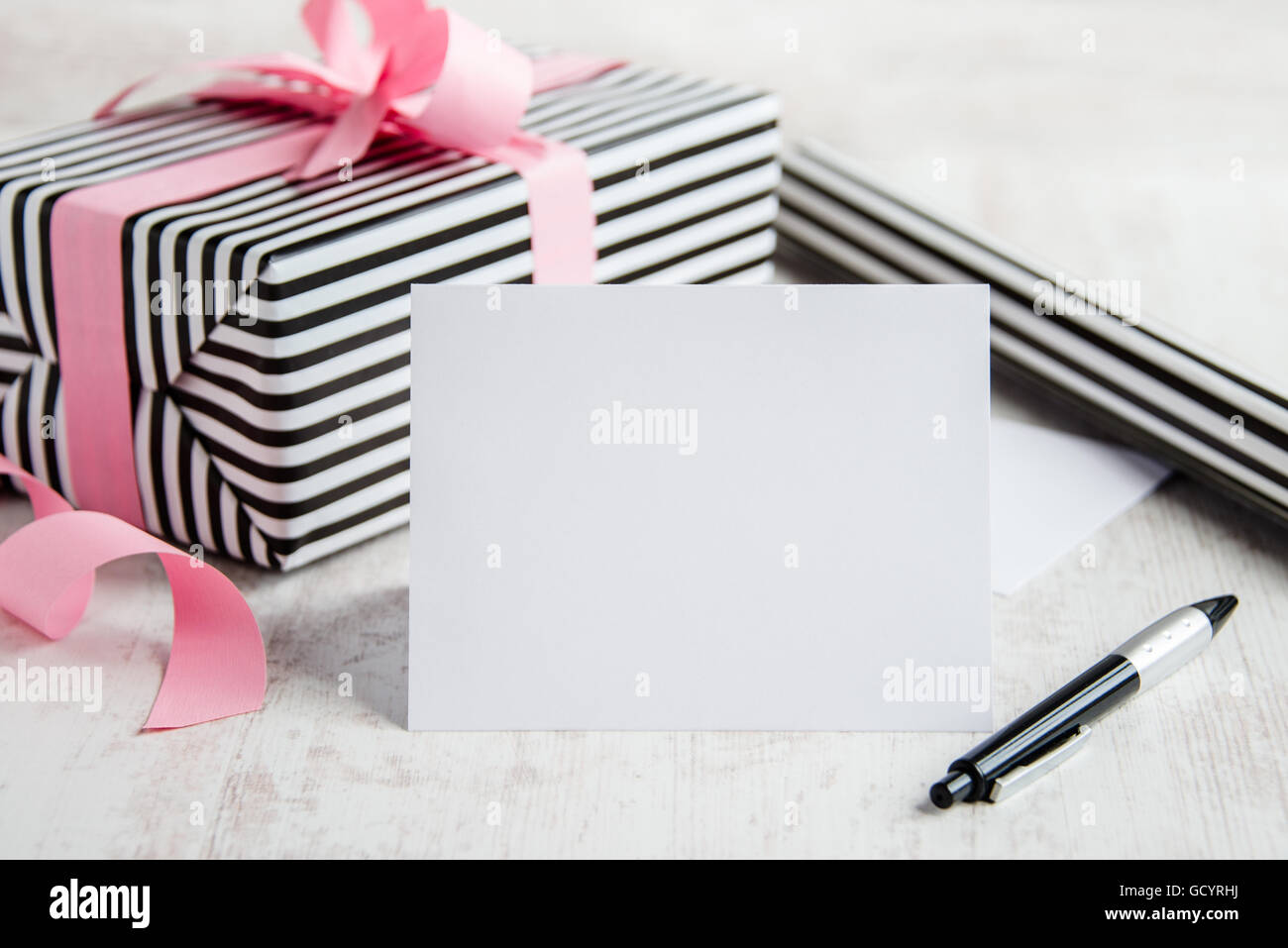 Empty greeting card with a pen. Wrapped gift and wrapping paper roll in ...