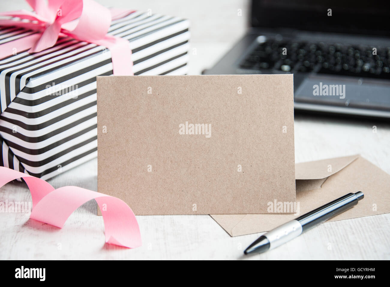 Empty greeting kraft card. Wrapped gift and a computer in the ...