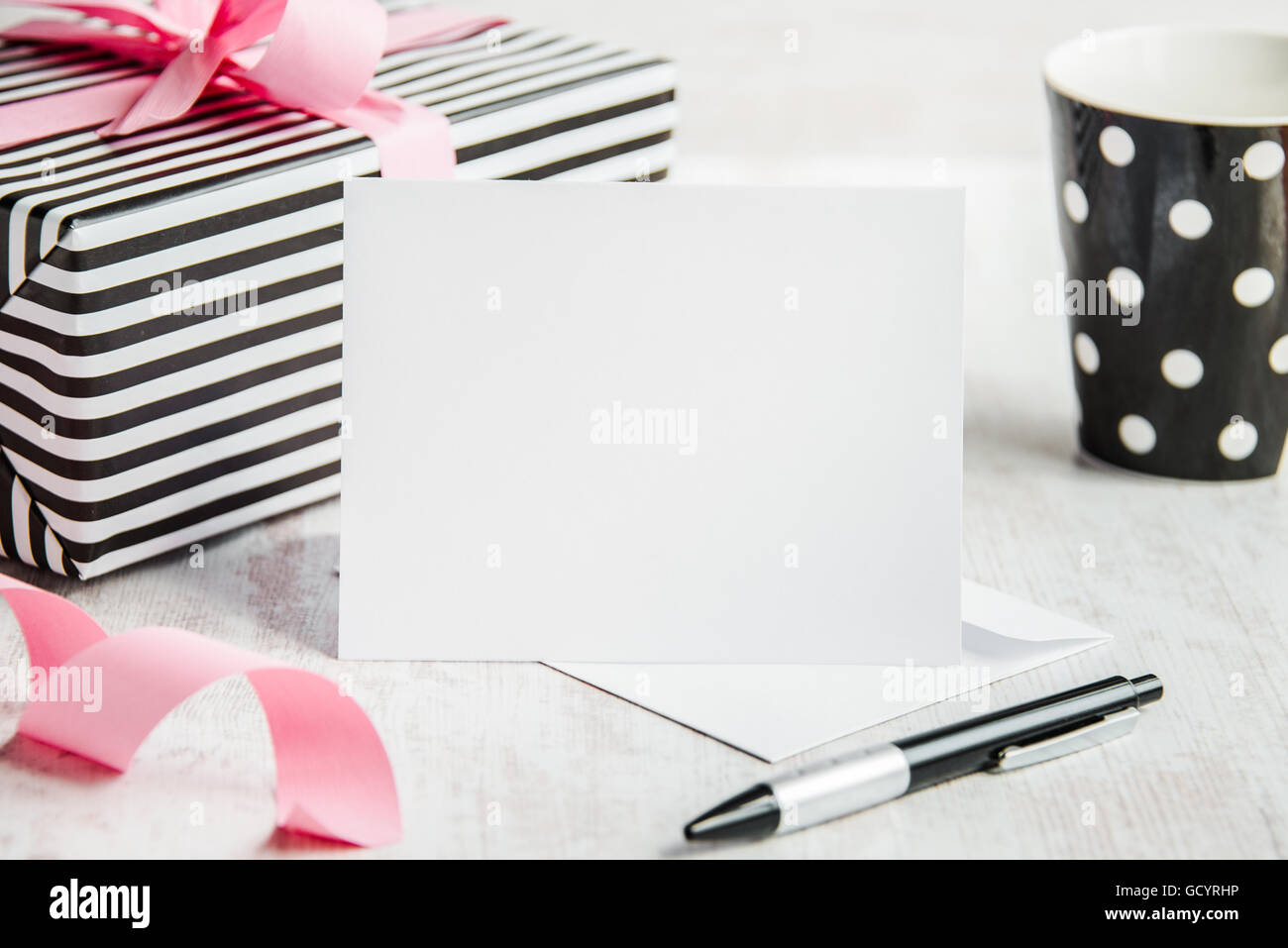 Empty greeting card. Wrapped gift and coffee cup in the background ...