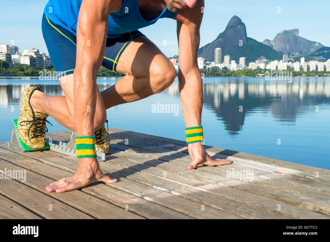 Track athlete with gold shoes crouching in starting blocks in front of ...