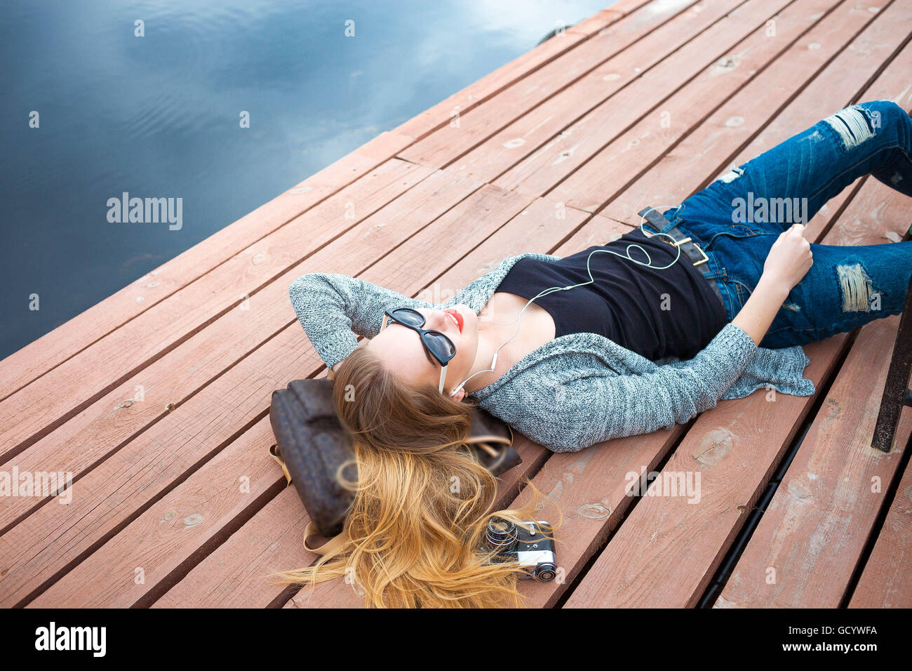 Young woman relaxing on pier Stock Photo - Alamy