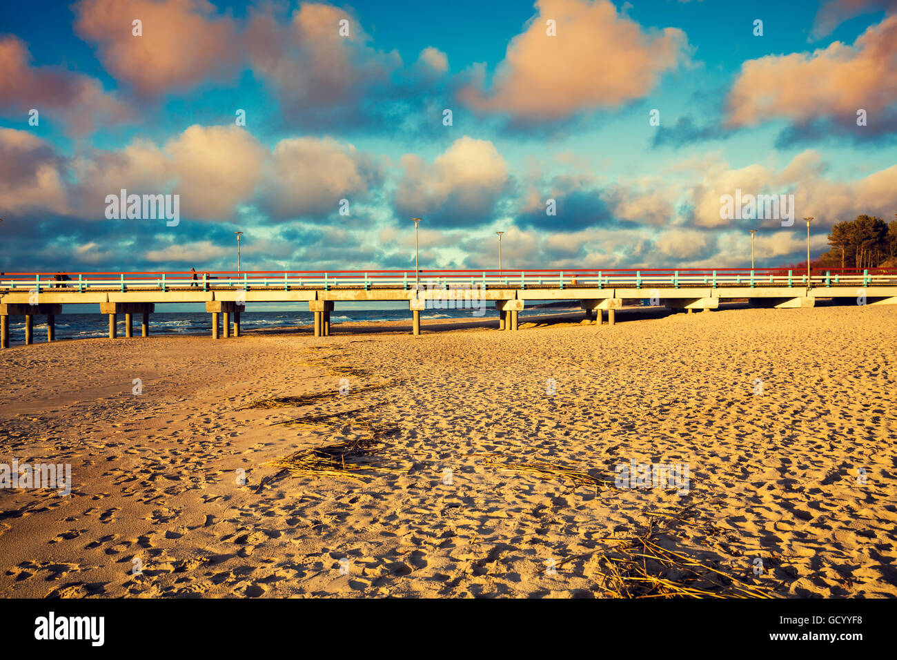 Pier on the beach at sunset light. Sky with clouds Stock Photo - Alamy
