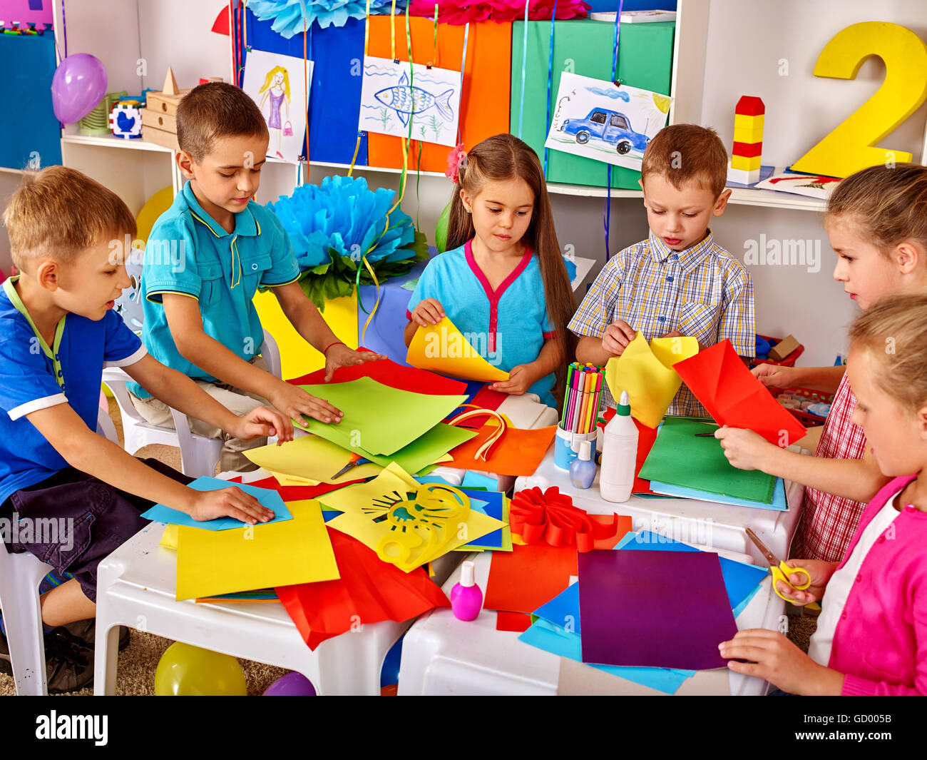 Kids holding colored paper on table in kindergarten Stock Photo - Alamy