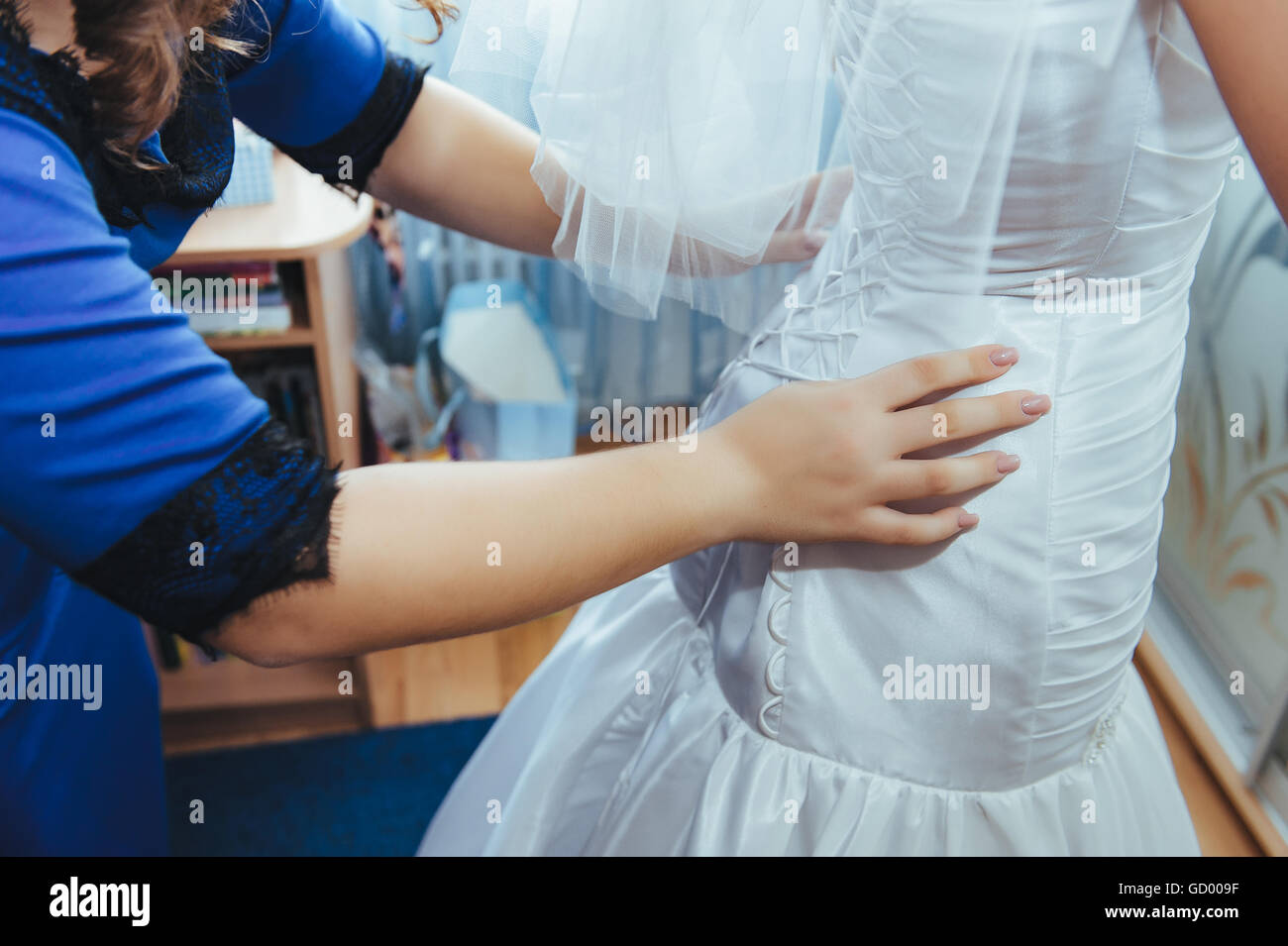 bridesmaids help dress bride gown Stock Photo - Alamy