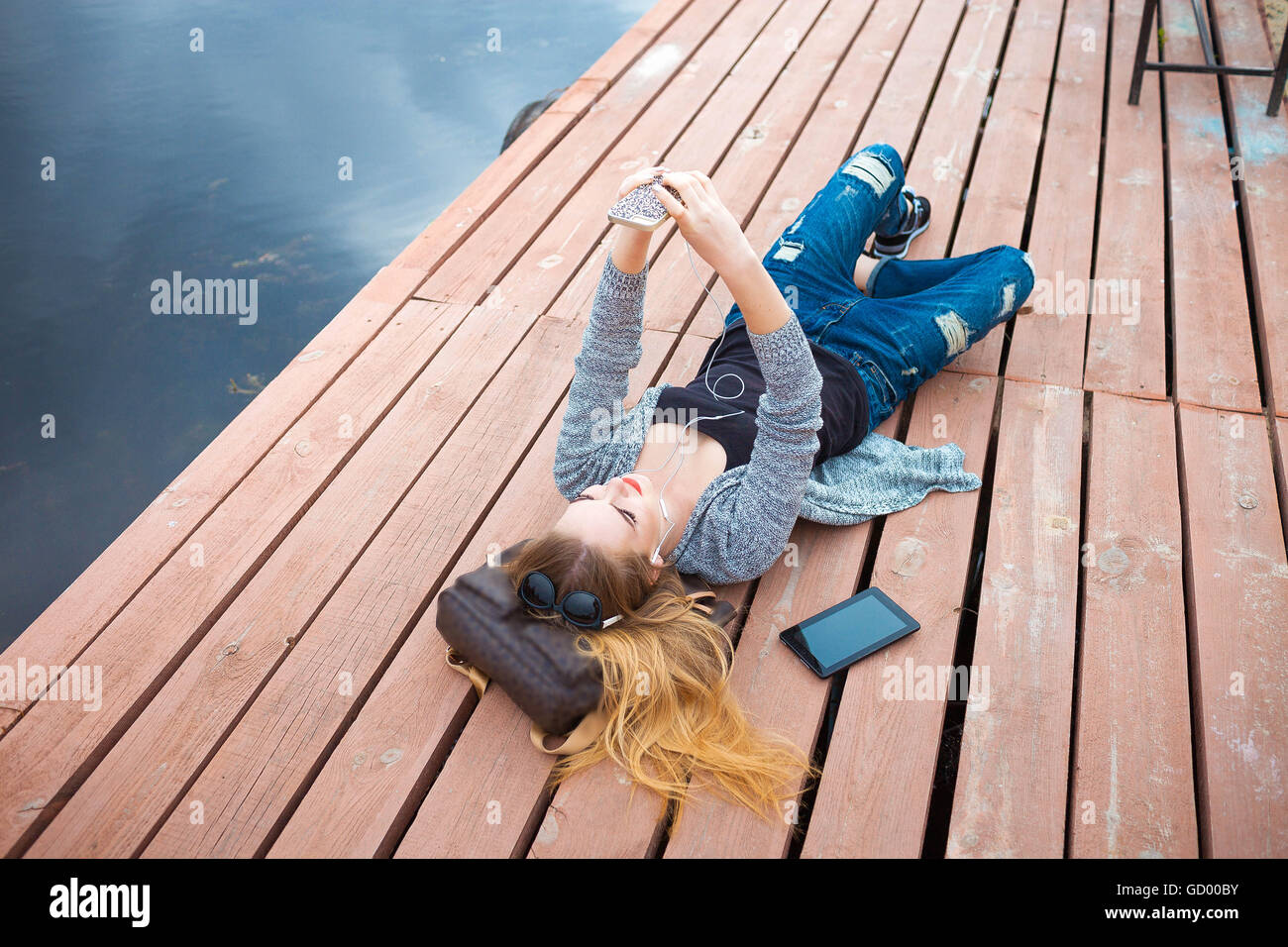 Young woman relaxing on pier Stock Photo - Alamy