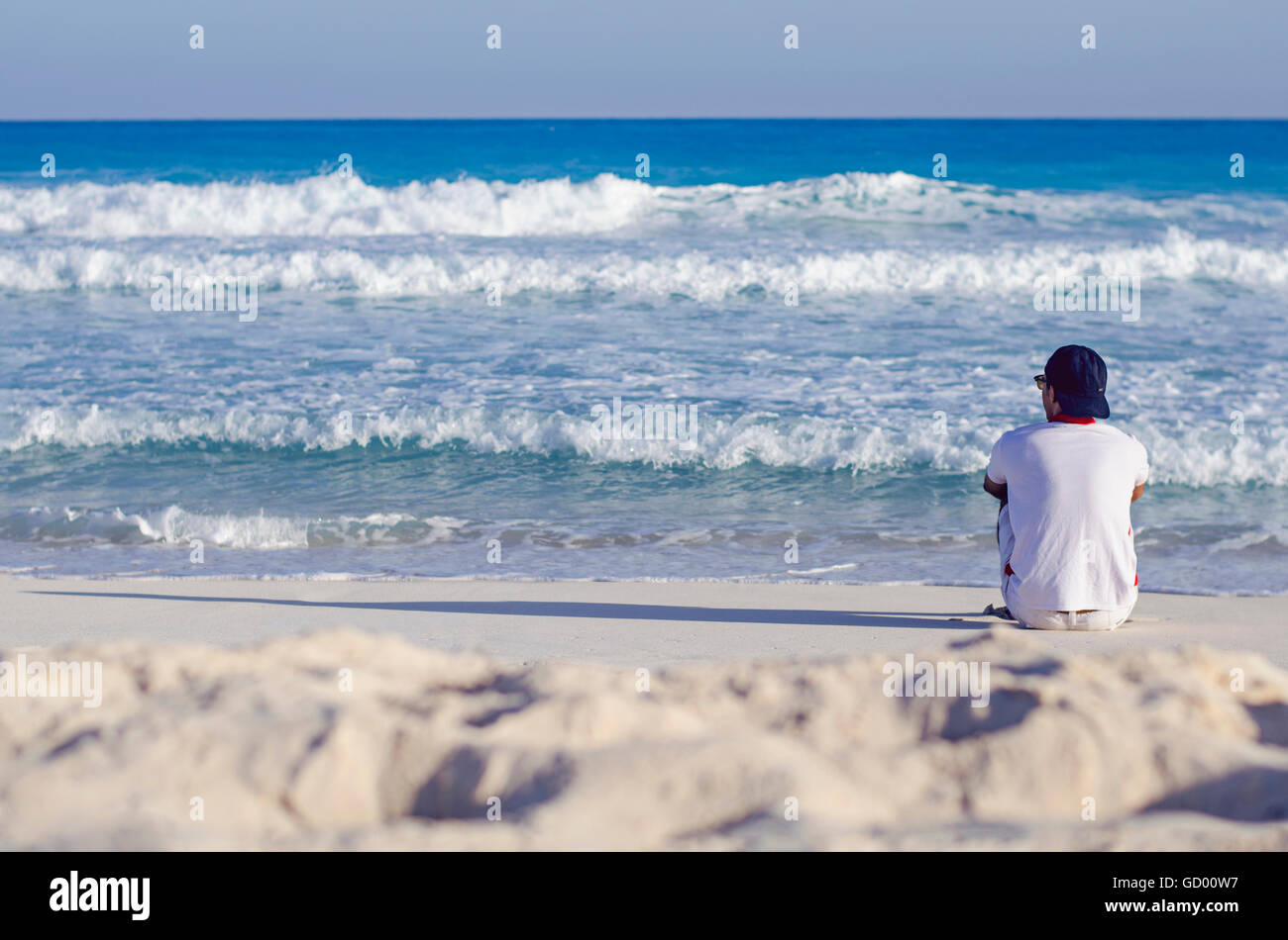 a man sitting alone looking towards the sea Stock Photo - Alamy