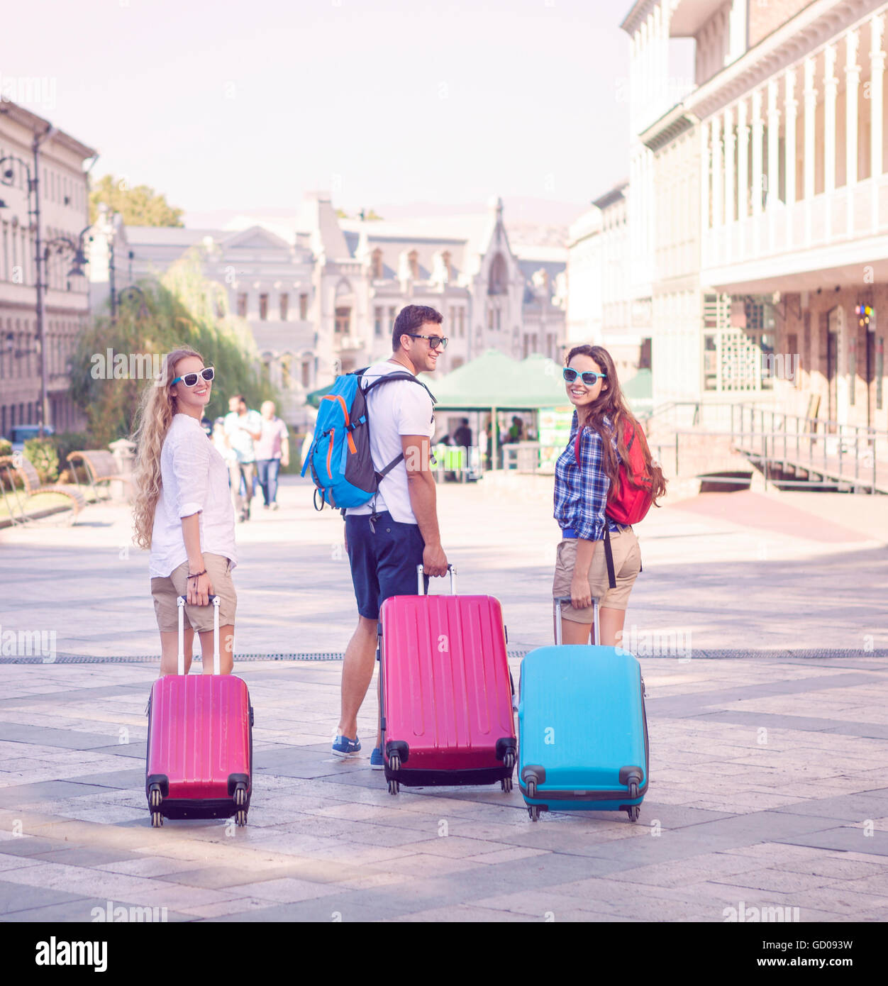 Travelers friends with luggage walking by street in the city. Selective ...
