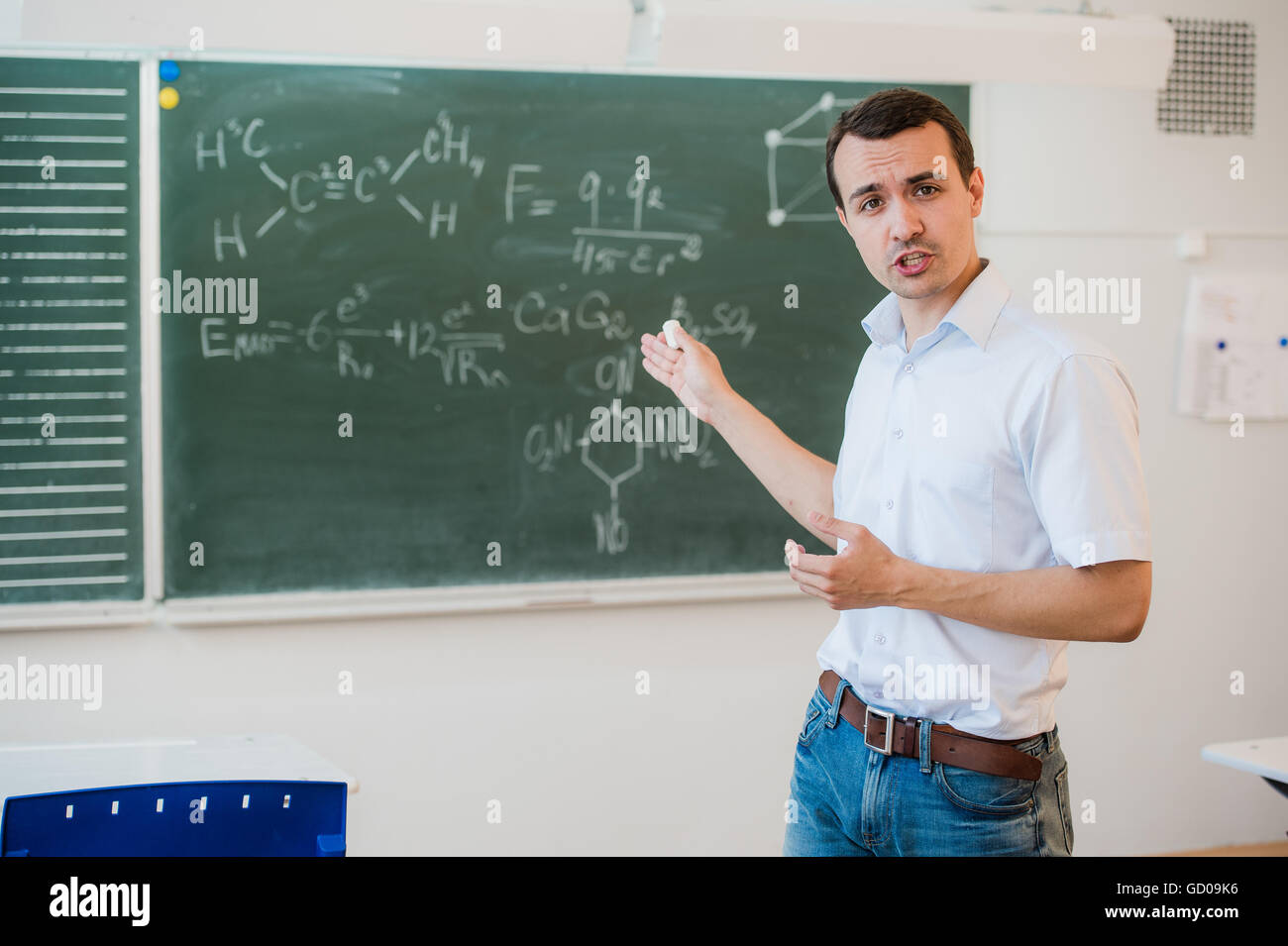 Young teacher near chalkboard in school classroom talking to class ...