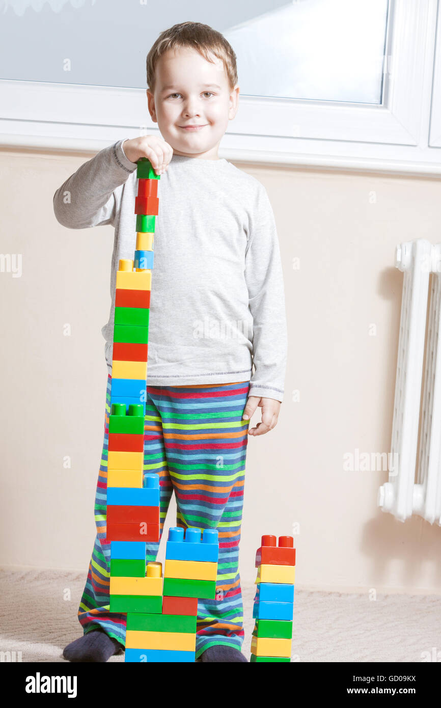 standing and smiling boy with built stack of colored cubes Stock Photo ...