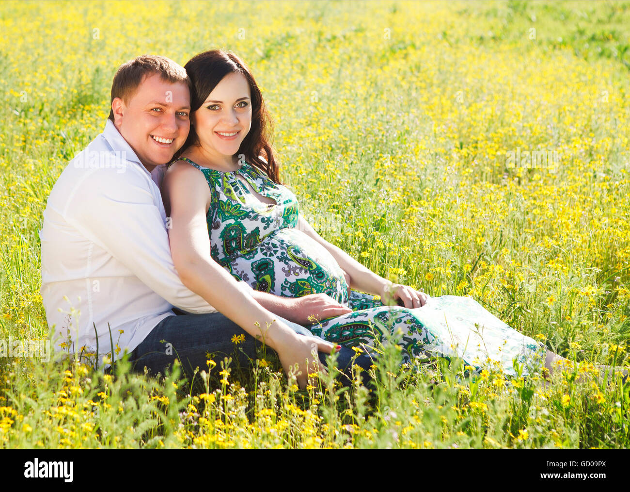 Young happy pregnant couple in the flowering spring park. Outdoors ...