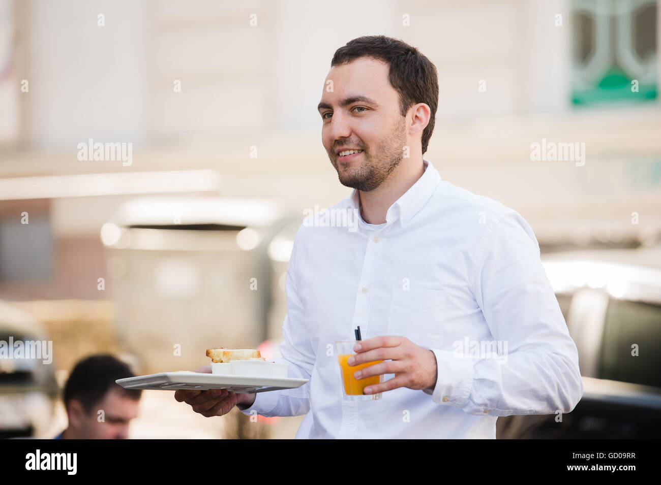 Portrait of happy waiter holding breakfast meal and orange juice at ...
