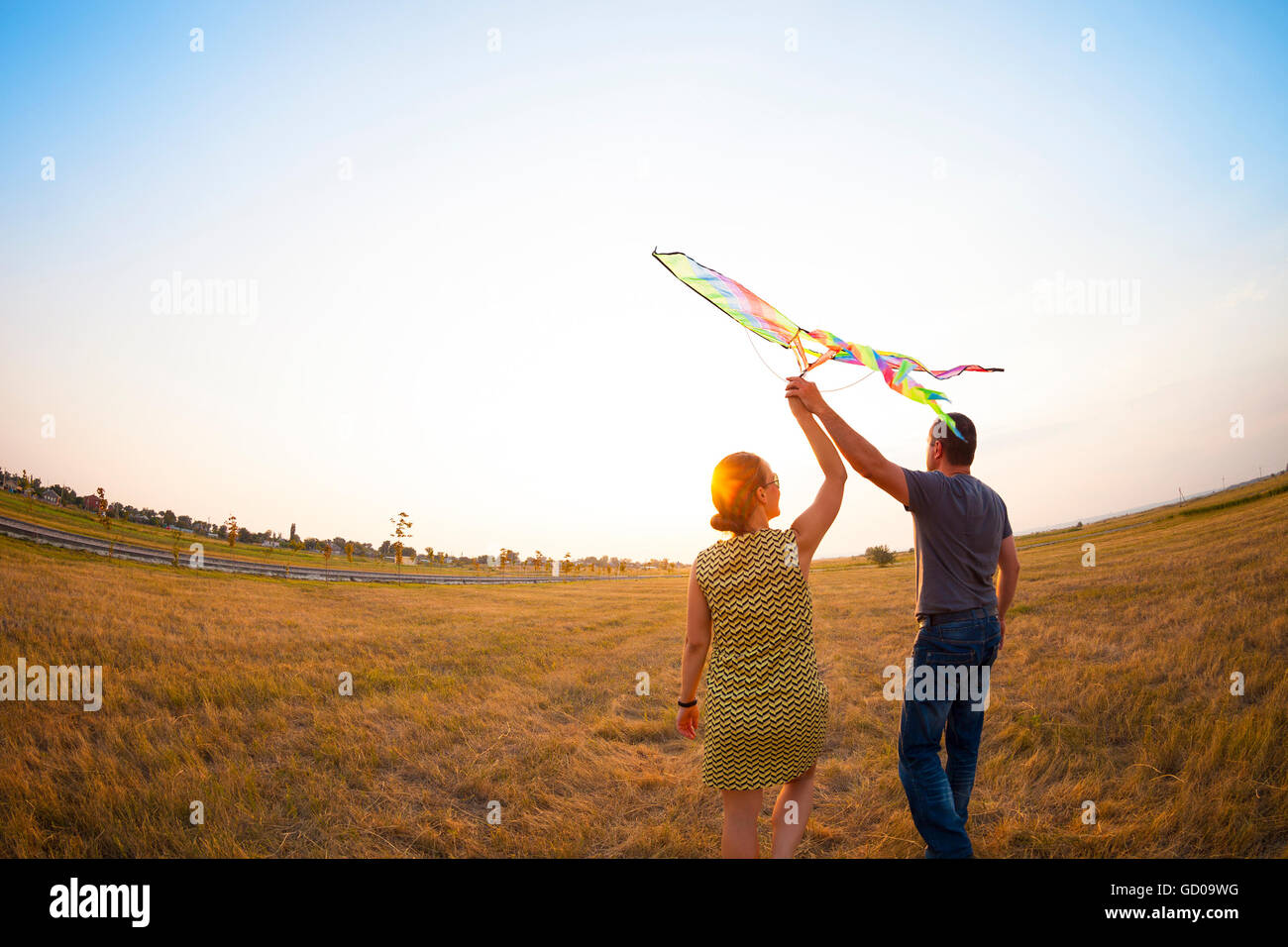 Happy young couple in love with flying a kite Stock Photo - Alamy