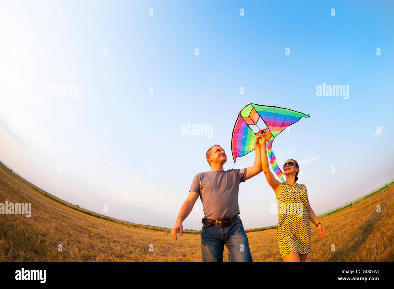 Happy young couple in love with flying a kite Stock Photo - Alamy