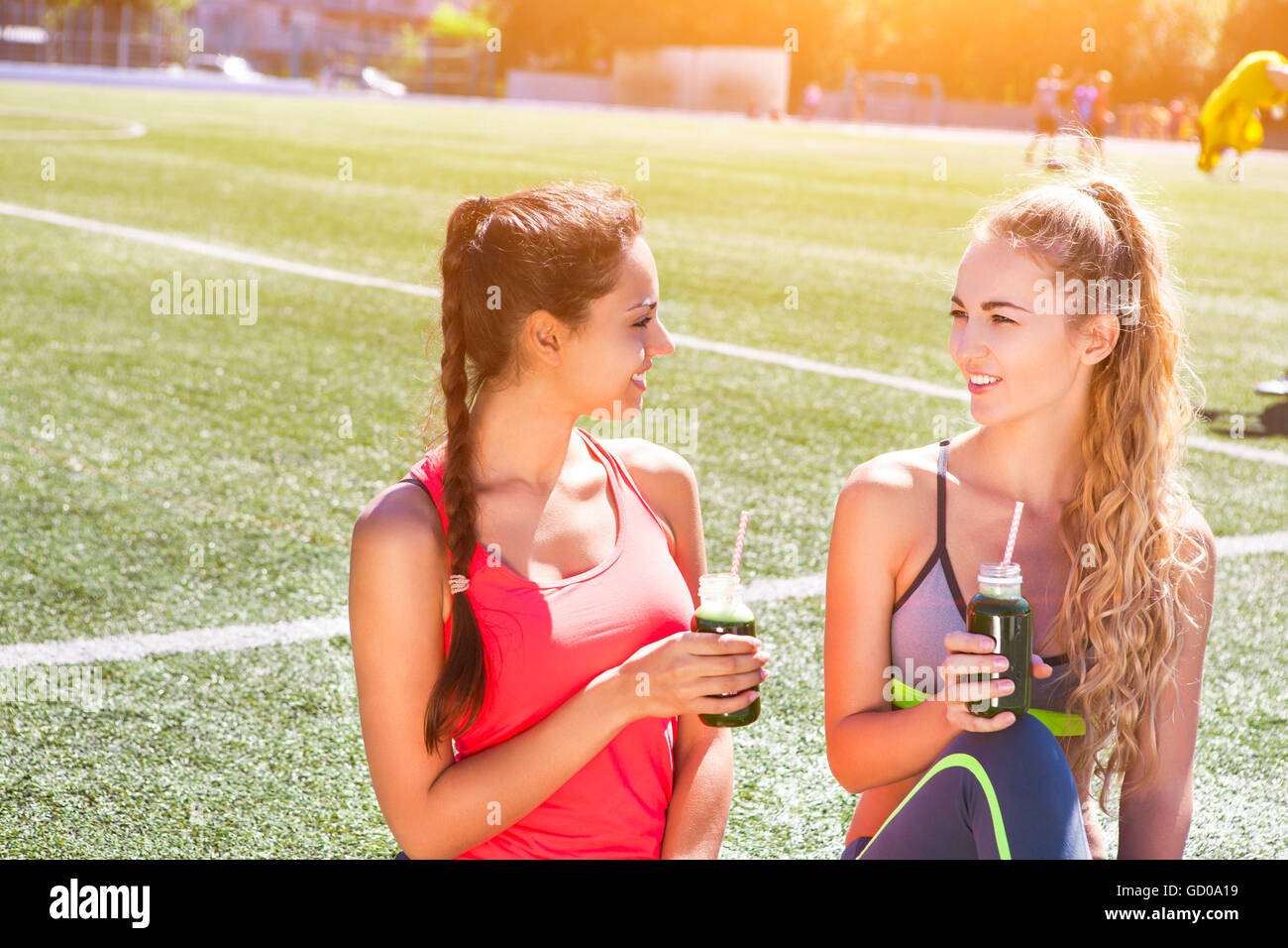 Two happy women drinking vegetable smoothie after fitness running ...