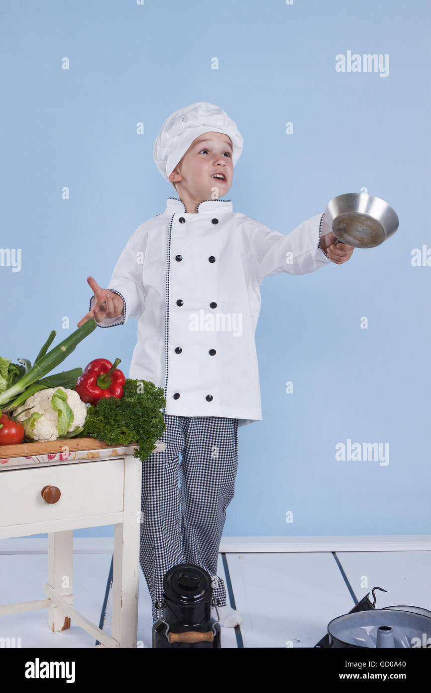 One little boy as chef cook making salad, cooking with vegetables ...