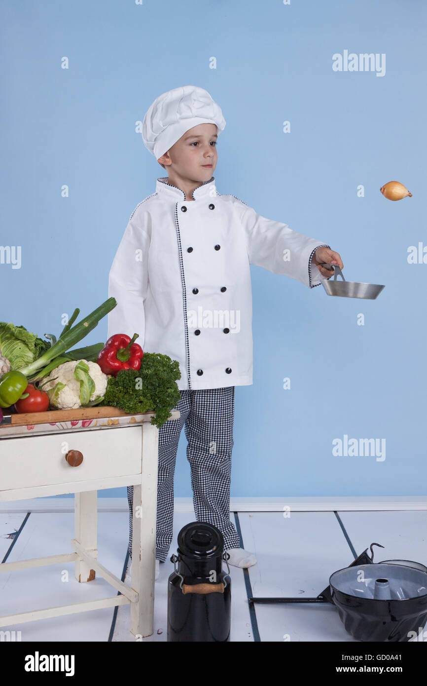 One little boy as chef cook making salad, cooking with vegetables ...