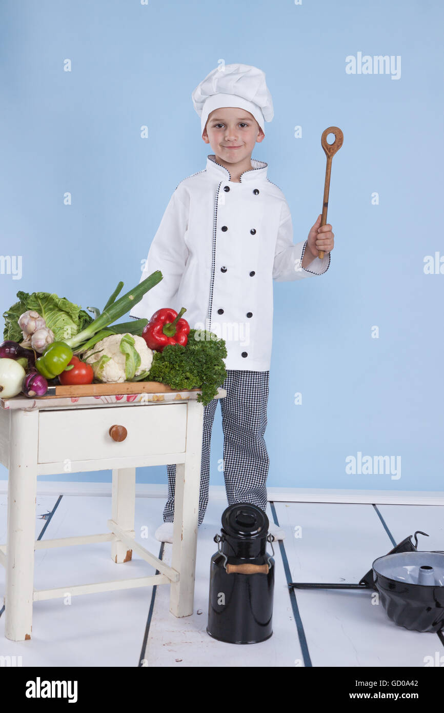 One little boy as chef cook making salad, cooking with vegetables ...