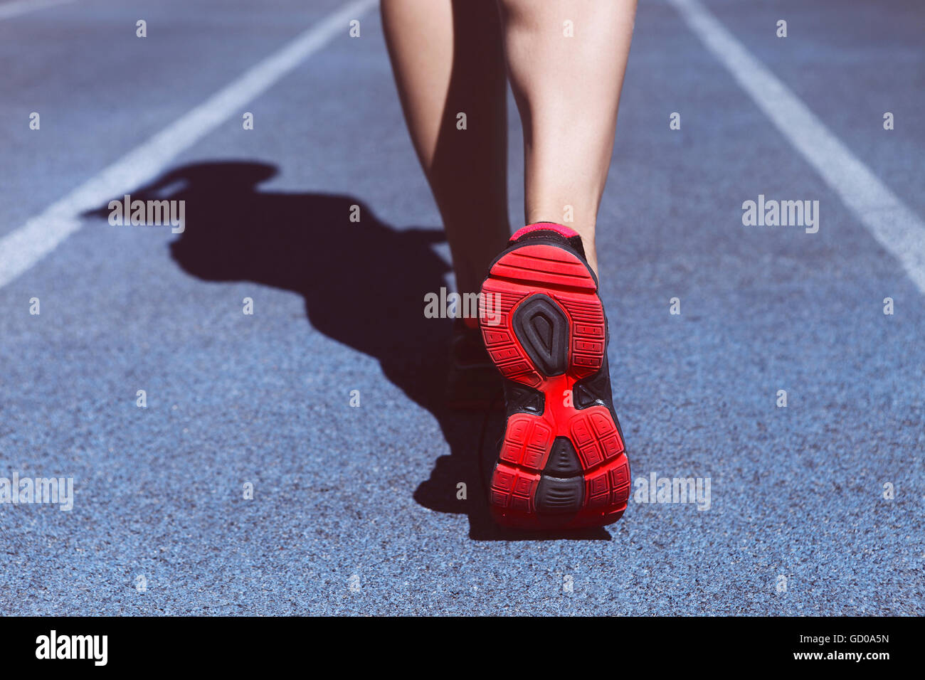 Athlete runner feet down stadium track. Closeup on female shoe and legs ...