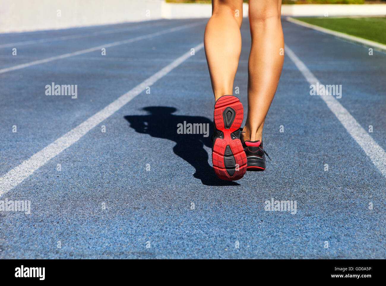 Athlete runner feet down stadium track. Closeup on female shoe and legs ...