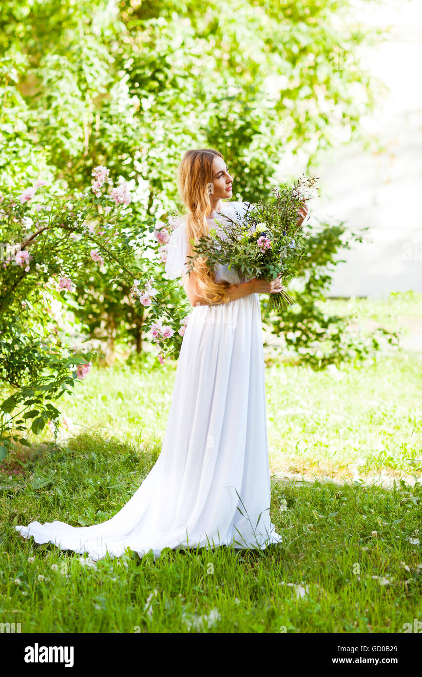 Happy bride with beautiful wedding bouquet of flowers in the style of ...