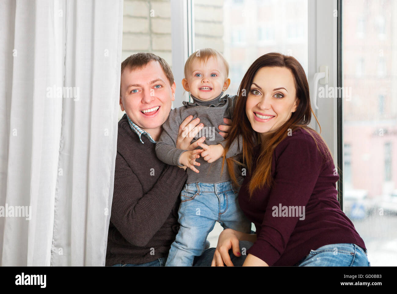 Young happy family with a child near the window at home Stock Photo - Alamy