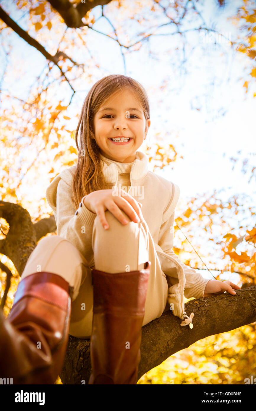 Happy little girl sitting on a tree trunk in a maple forest Stock Photo ...