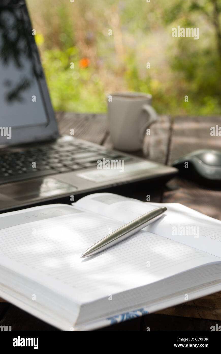 Pen, notebook and laptop on garden background Stock Photo - Alamy