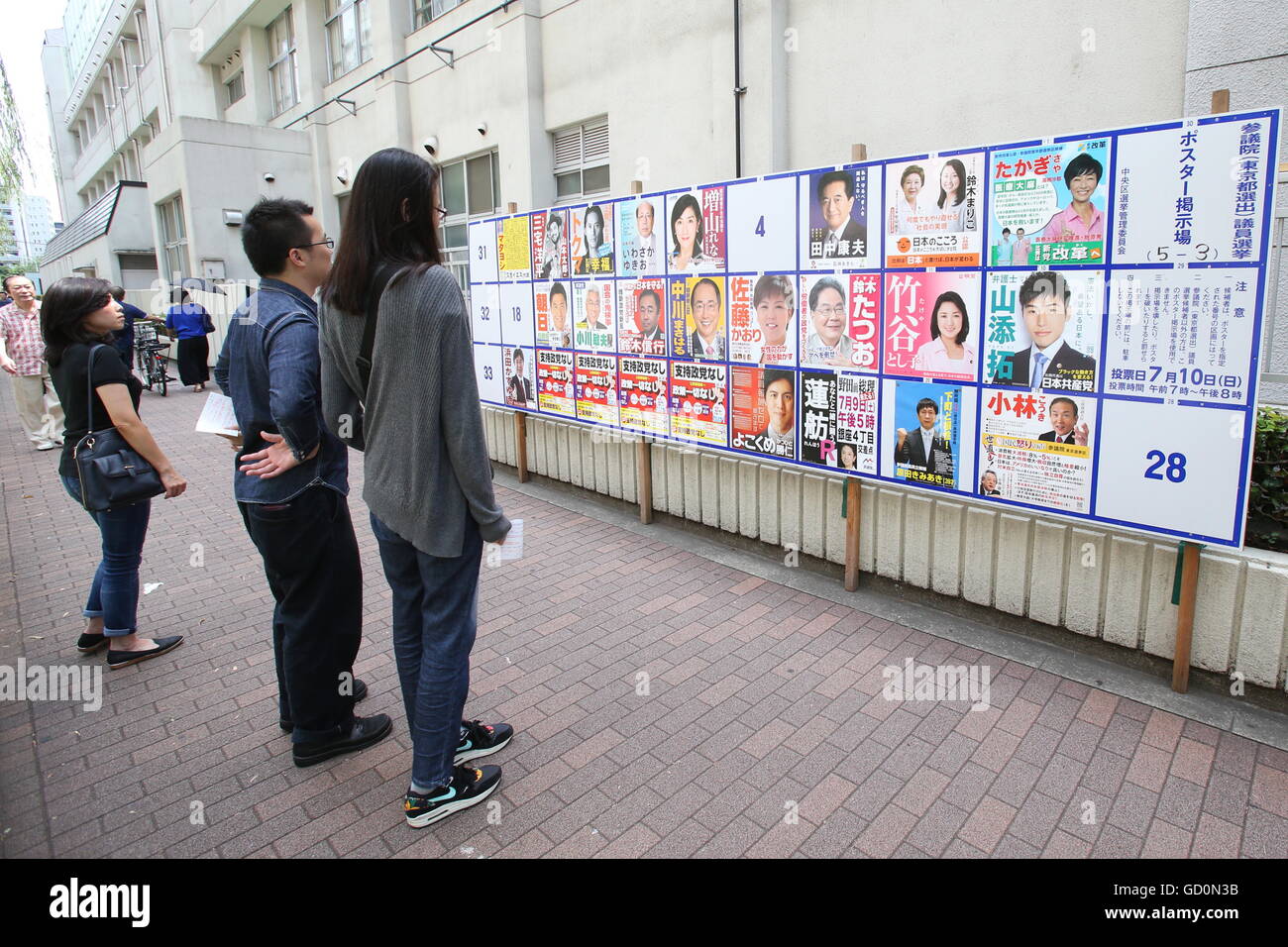 Voters look a board displaying posters of local candidates for Japan's ...