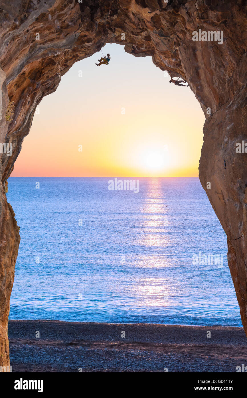 Deep high Cave on Seafront and extreme Climbers on Sunrise Stock Photo ...
