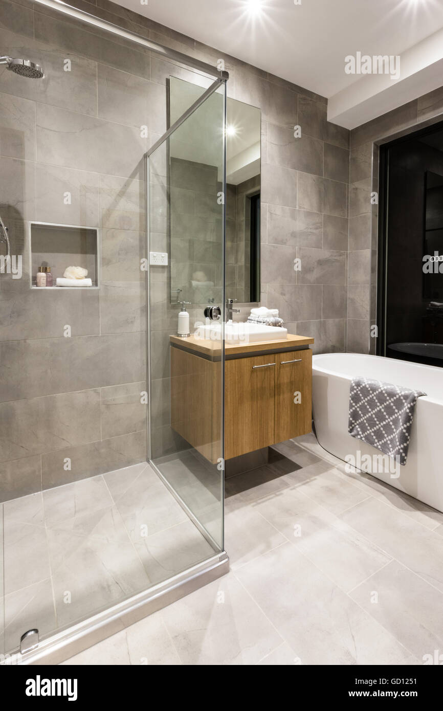 Modern bathroom with a shower area covered with glass next to a wooden ...