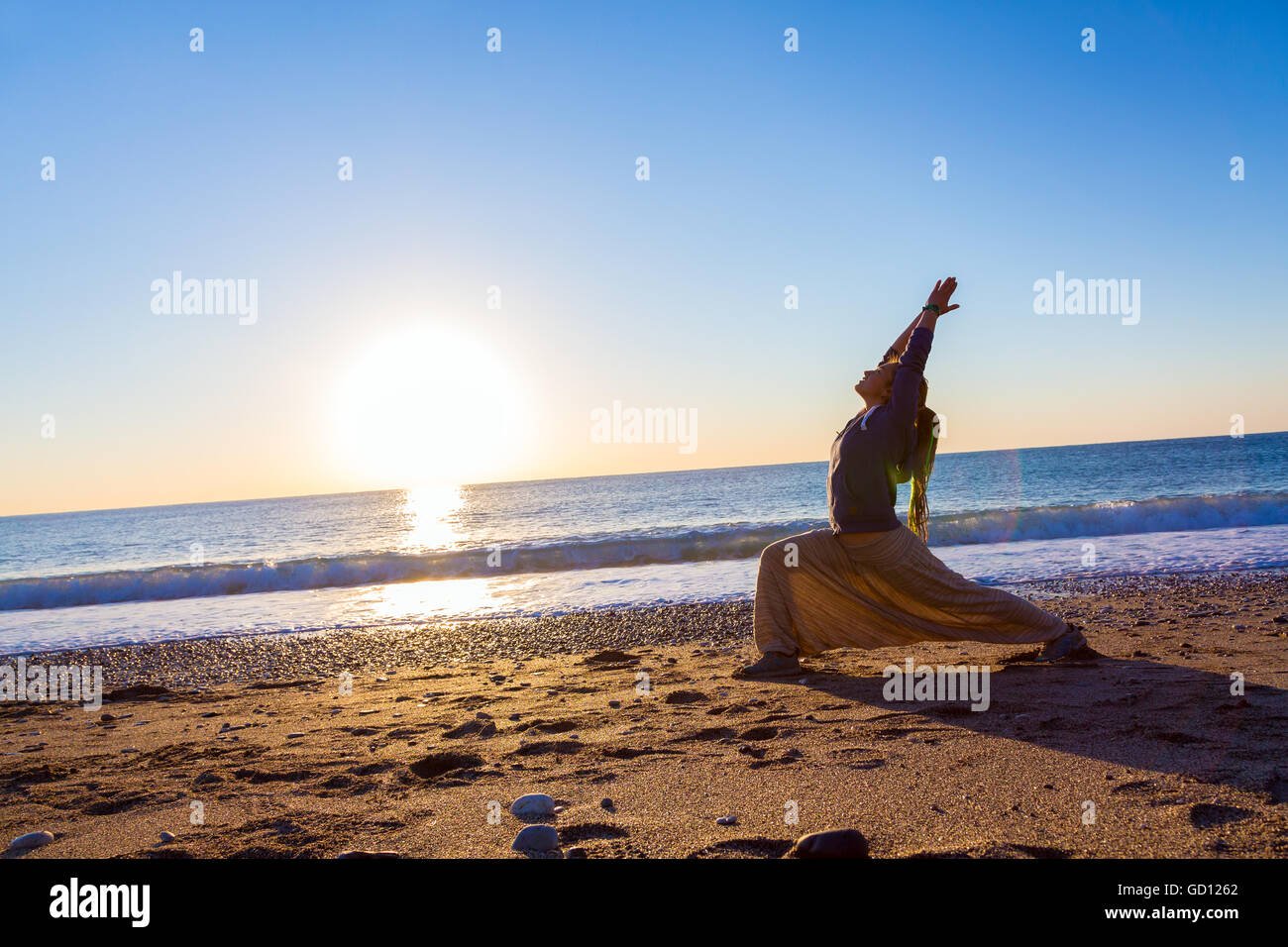 Young Woman doing yoga Exercise on tropical Beach at Sunrise Stock ...