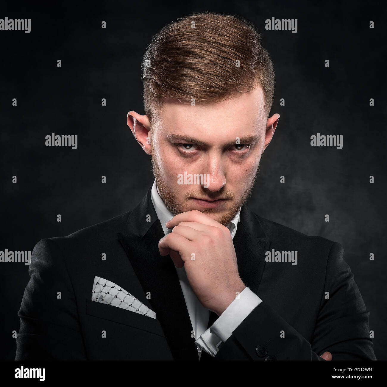 Elegant young man in suit looking frowning on dark background Stock ...