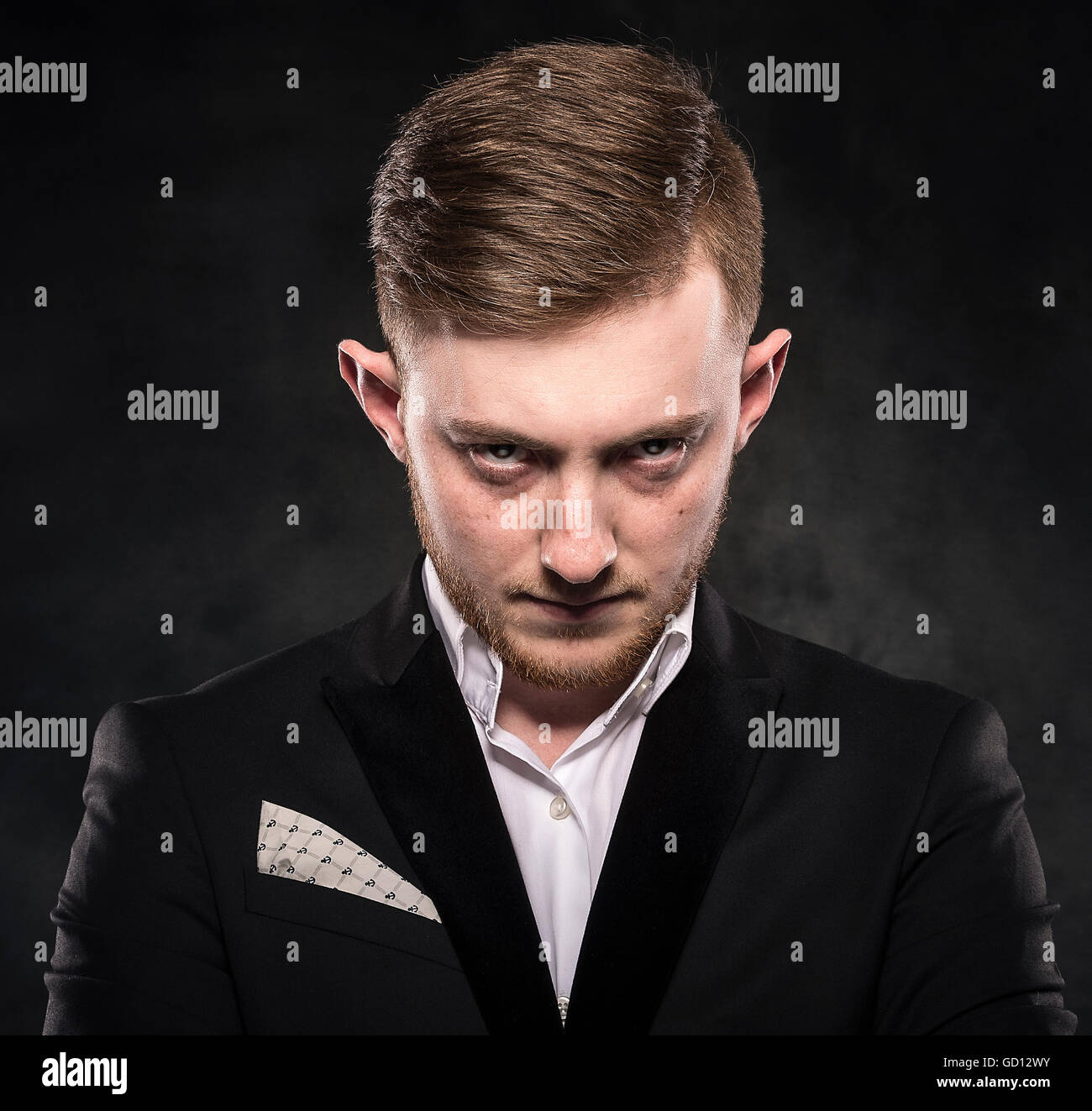 Elegant young man in suit looking frowning on dark background Stock ...