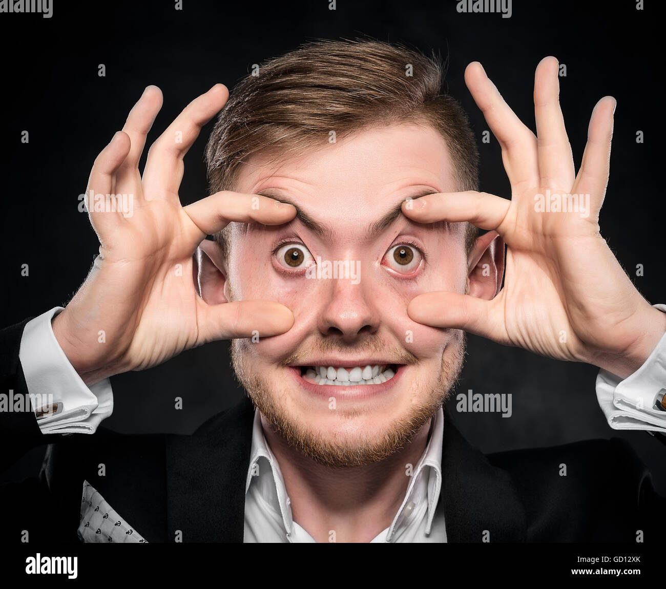 Man in suit makes funny face over dark background Stock Photo - Alamy