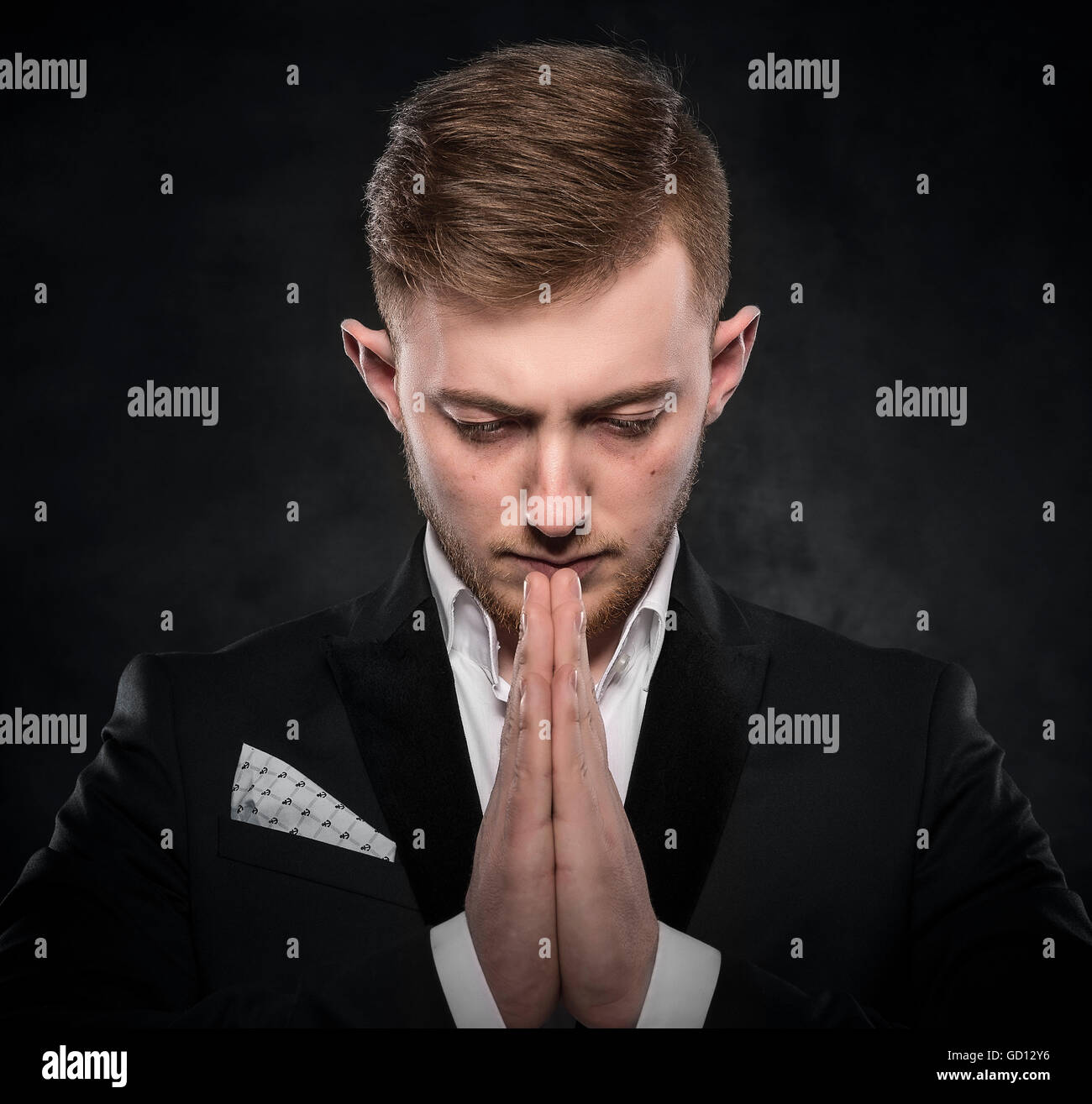 Portrait of businessman praying or thinking over dark background Stock ...