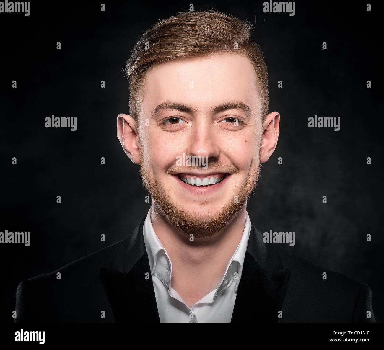 Young handsome man in suit smiling on dark background Stock Photo - Alamy