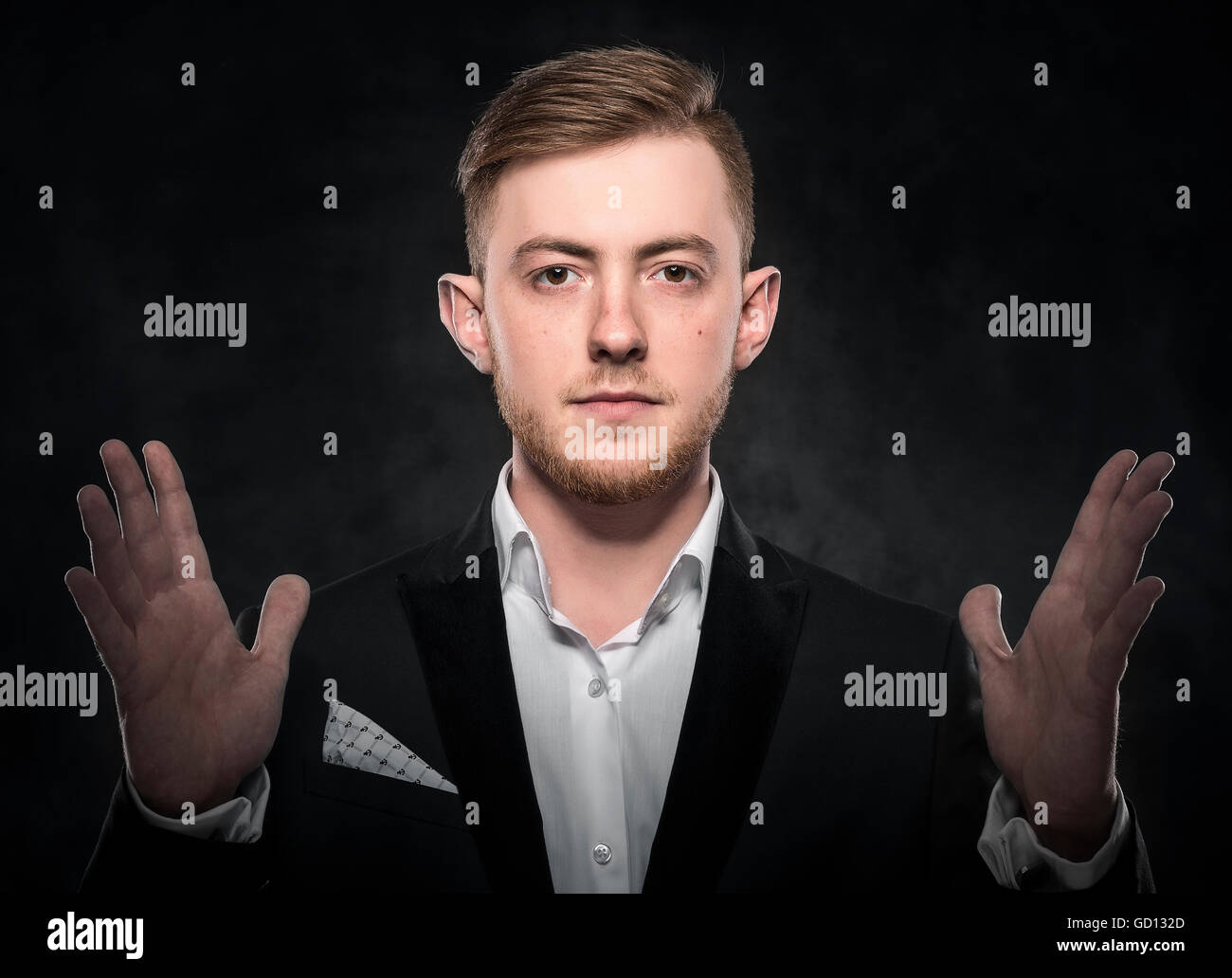 Man covering his ears over dark background Stock Photo - Alamy