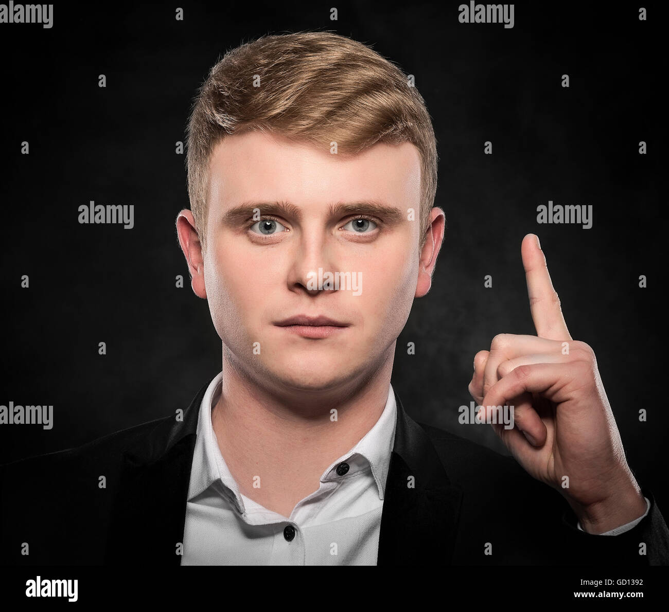 Idea. Young man shows finger up over darck background Stock Photo - Alamy
