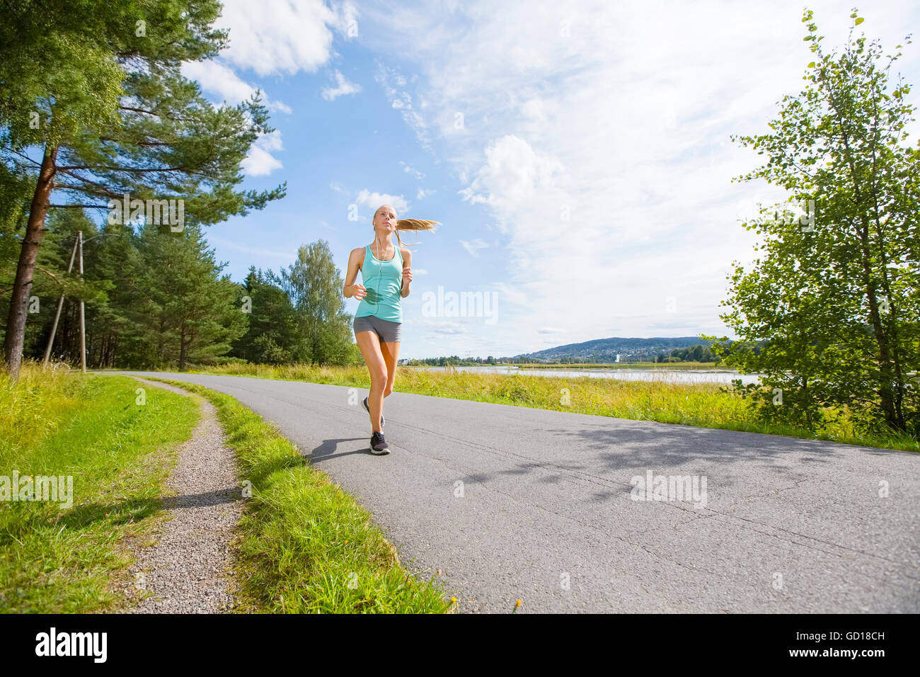 Young woman runs fast on a road in the forest Stock Photo - Alamy