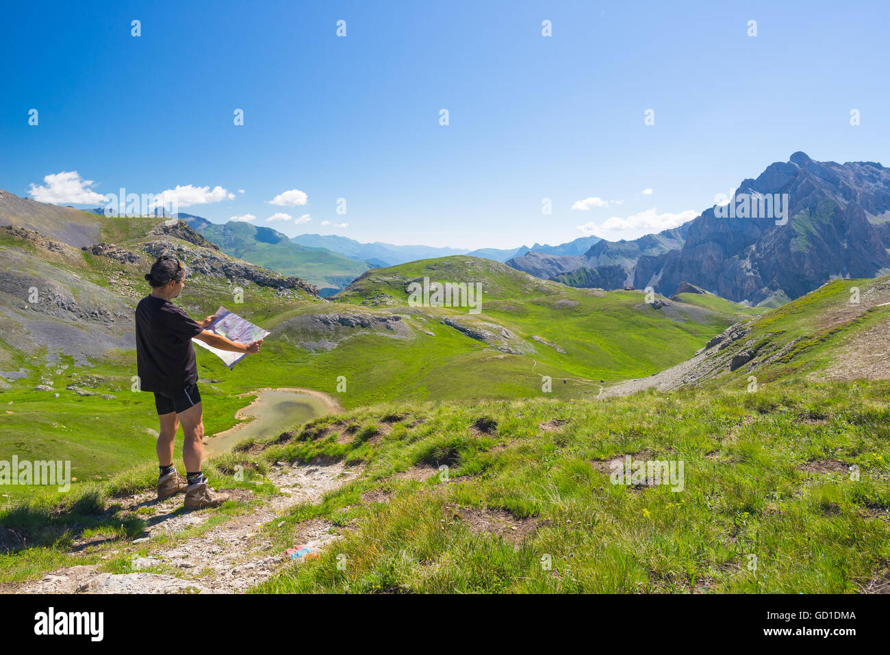 Hiker reading trekking map while resting at panoramic mountain spot ...