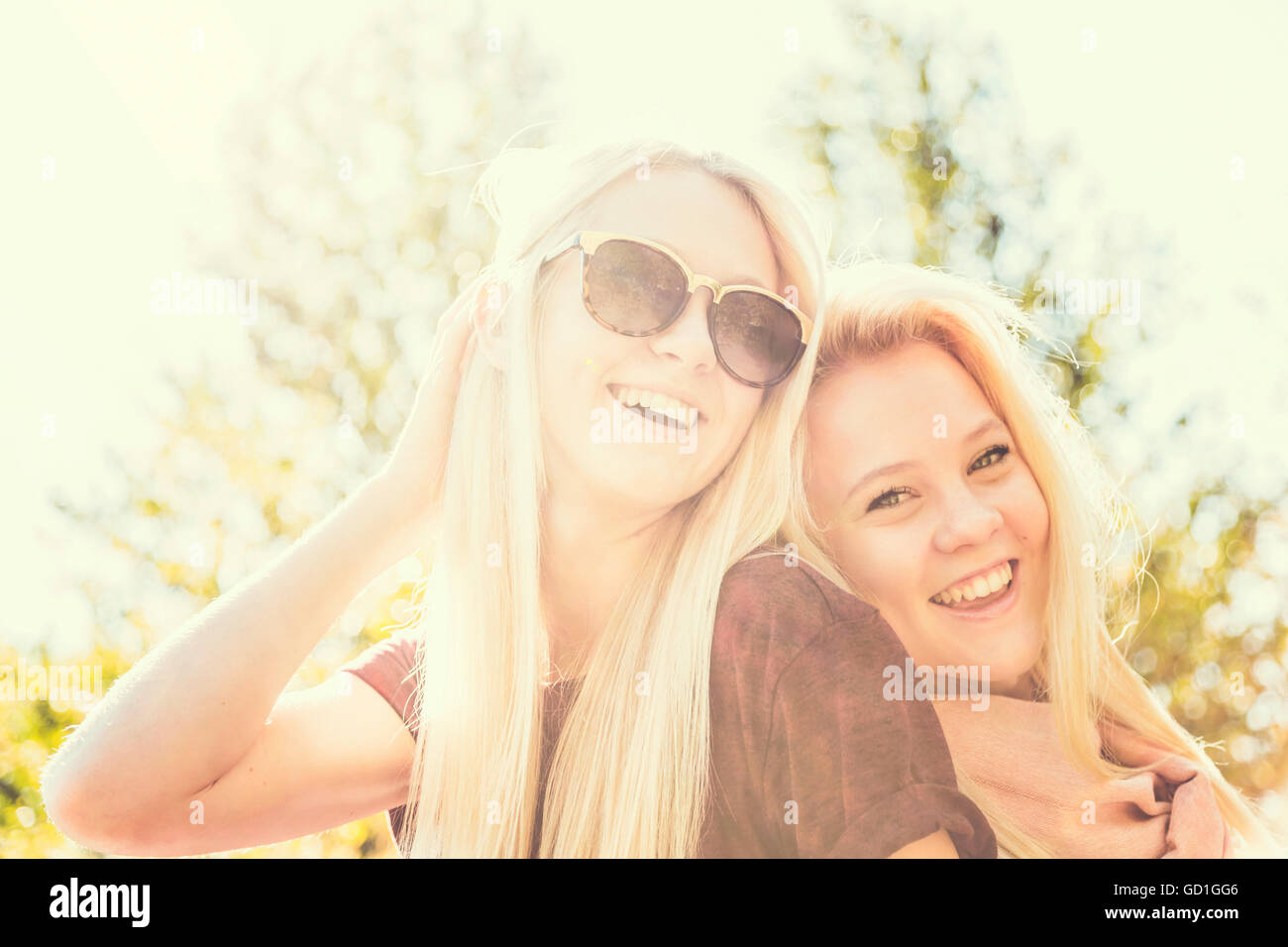 Two sisters having fun together outdoors in a city park in autumn and ...